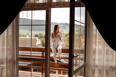 아침에 커피 광석 차 한 잔을 들고 발코니에 젊은 여자 그녀는 호텔 방에서 수메르의 자연을 바라보고 있습니다 소녀는 세련된 잠옷을 입고있다 시간을 휴식 산에 대한 스톡 사진