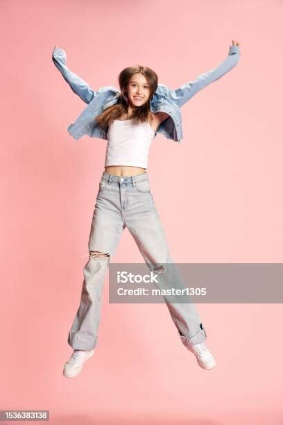 어린 아름 다운 소녀 분홍색 스튜디오 배경에 뛰어 드는 캐주얼 한 옷을 입은 학생의 전체 길이 초상화 성공 유행하는에 대한 스톡 사진 및 기타 이미지 Istock