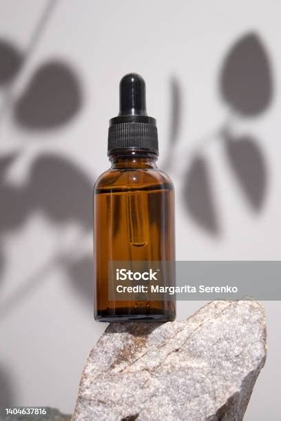 화장품 병 세럼 돌 위에 기름은 회색 배경에 그림자 분지 유칼립투스와 함께 서 있습니다 천연 화장품 개념 스킨 케어 제품 얼굴