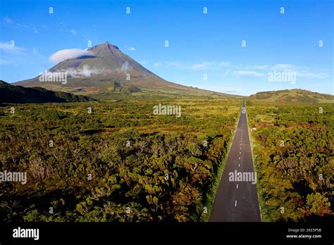 Aerial View Of A Road Passing Ponta Da Pico Partly Covered In Cloud With Clear Sky Near Lagoa Do