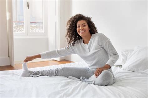 Premium Photo Smiling Woman Engaging In Morning Stretch Routine On Bedroom Bed