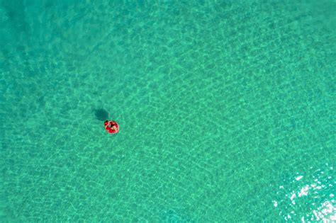 세이셸의 투명한 청록색 바다에서 수영 링 도넛에서 수영하는 슬림 한 여성의 공중 보기 소녀와 여름 바다 풍경 아름다운 파도 다채로운 물 드론에서 보기 공중 뷰에 대한 스톡