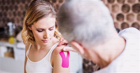 젊은 여성 환자에게 테이프를 붙이는 선임 남성 물리치료사 사진 Unsplash의 운동 이미지