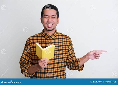 Adult Asian Man Smiling While Holding A Book And Pointing To The Left Stock Image Image Of