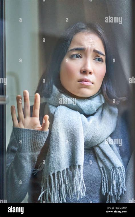 Vertical Shot Of Upset Asian Woman Looking Outside Touching Window