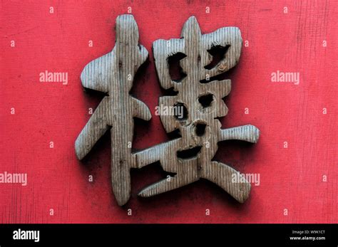A Close Up Of A Wooden Chinese Character On A Red Painted Wall Stock