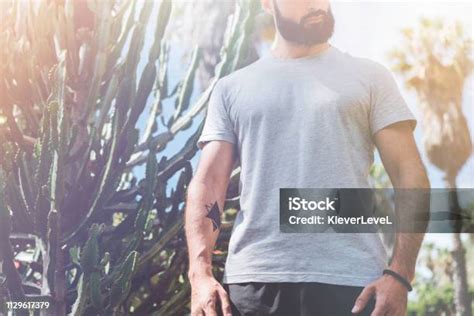 Hipster 캐주얼 도시 스타일에 회색 공백 T셔츠와 귀하의 로고 또는 디자인에 대 한 공간을 가진 검은 Snapback 모자를 착용 하는 수염과 잘생긴 남성 모델 그린