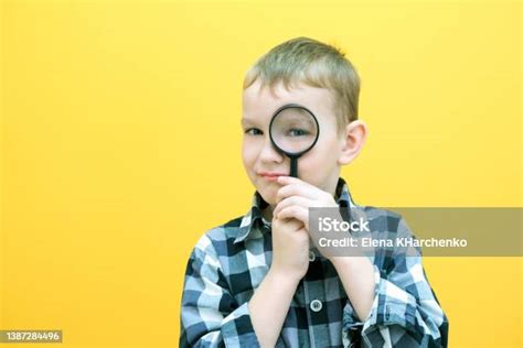 캐주얼 한 옷을 입은 긍정적 인 호기심 많은 여학생이 노란색 배경에 돋보기를 통해 카메라를 봅니다 과학에 대한 스톡 사진 및 기타 이미지 Istock