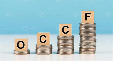 Wooden Blocks Spelling Out Ocf On Stacks Of Coins Against A Blue