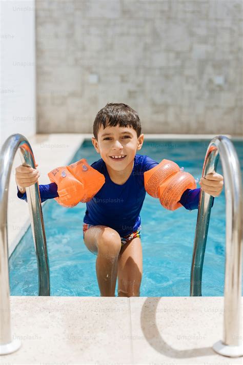 수영장에 팔이 떠 있는 수영복을 입은 달콤한 어린 소년 사진 Unsplash의 투명한 이미지