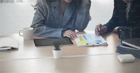 디지털 태블릿을 사용하는 두 명의 비즈니스 동료가 사무실에서 종이에 비즈니스 데이터를 분석하는 장면을 자릅니다 사진