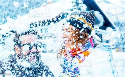 눈이 내리는 겨울의 재미있는 여가 활동 행복한 사람들은 겨울 휴가 시즌에 눈덩이와 눈이 함께 놀면서 즐거운 시간을 보냅니다 남자와 여자가 즐기고 있습니다 장난기 많은 성숙한