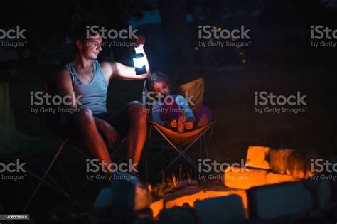 아빠와 딸은 자연 속에서 여름에 야외에서 화재에 의해 밤에 앉아있다 가족 캠핑 여행 캠프 파이어 주위에 모임 아버지의 날 바베큐