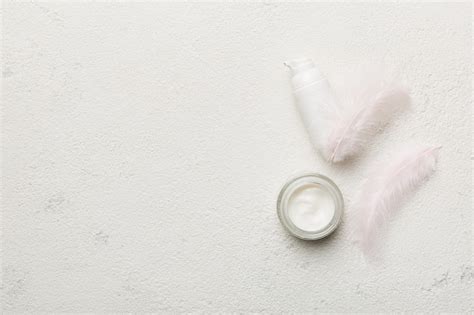 타조 깃털이있는 분홍색 파스텔 배경에 스킨 케어 세럼 세트 스파 화장품 크림 항아리 브랜딩 모형 복사 공간이있는 상판 깃털에