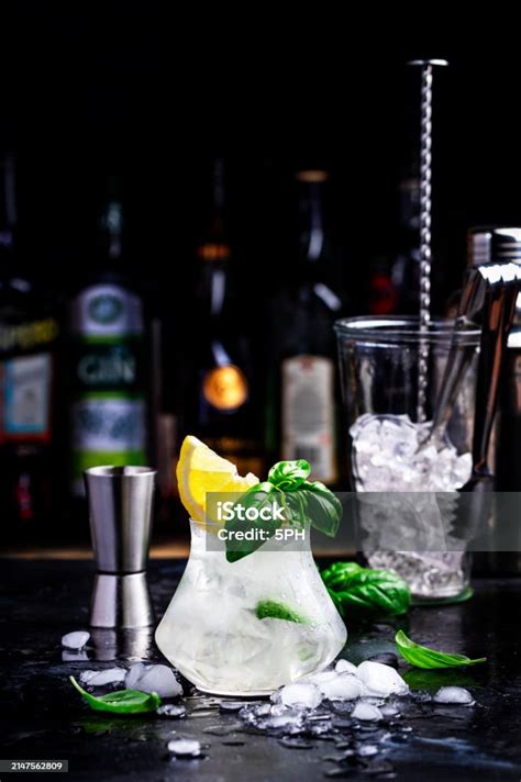 메즈칼 리큐어 설탕 시럽 레몬 주스 그린 바질 향신료 및 으깬 얼음 다크 바 카운터 배경을 곁들인 여름 아이스 칵테일 음료 검은