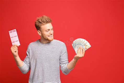 Portrait Of Happy Young Man With Money Fan And Lottery Ticket On