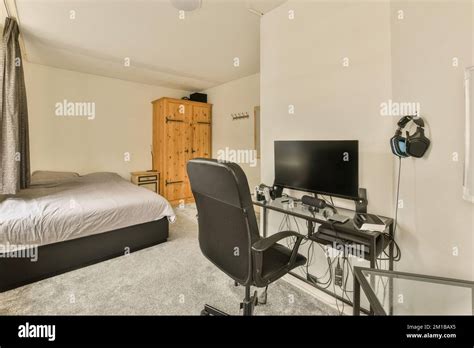 A Bedroom With A Bed Desk And Television Set Up In The Corner Of The Room To Watch Tvs Stock