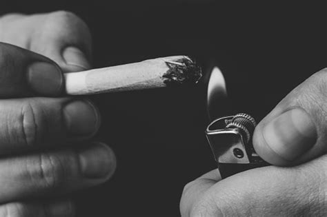 남자는 그의 손에 마리화나 대마초 조인트와 라이터를 연기가 난다 연기가 검은 배경에 의료 마리화나 사용과는 대마초의 합법화의 개념 흑인과 백인 건강관리와 의술에 대한 스톡