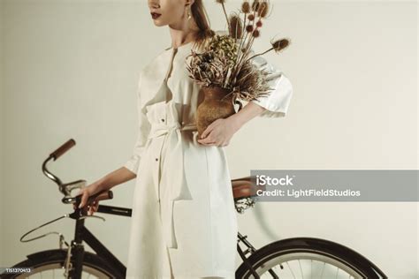 자전거 근처의 건조 한 꽃의 꽃다발과 포즈 세련 된 여자의 자른 보기 두발자전거에 대한 스톡 사진 및 기타 이미지 두발자전거 말린 식물 베이지 배경 Istock
