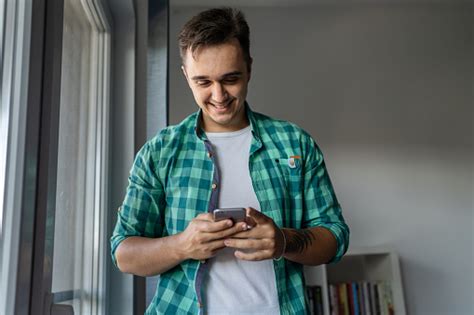 집에 서서 휴대 전화를 사용하여 메시지를 보내거나 전화를 거는 한 남자 20 24세에 대한 스톡 사진 및 기타 이미지 20