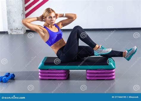 Woman Sitting On Step Platform And Doing Press Aerobic Having Work Out In Fitness Club Stock