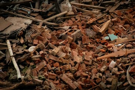 창문에서 오래된 건물을 파괴하는 건설 현장의 전망 벽돌과 모든 가구가 거대한 크레인 발톱으로 들어 있습니다 사진 Unsplash의 땅 이미지