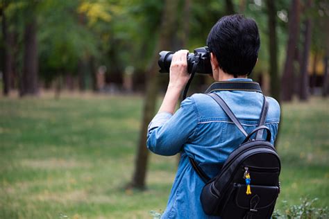 야외에서 사진을 찍는 여성 사진작가 배낭 들고 카메라와 파란색 데님 셔츠를 입고 짧은 머리와 젊은 갈색 머리 후면 보기 공간을 복사합니다 40 44세에 대한 스톡 사진 및