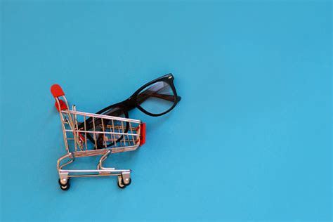 파란색 배경의 작은 장바구니에 검은 색 플라스틱 프레임에 있는 어린 아이들을 위한 어린이 용 안경 복사 공간 어린이 용 안경용 특수 파손 방지 프레임 0명에 대한 스톡 사진