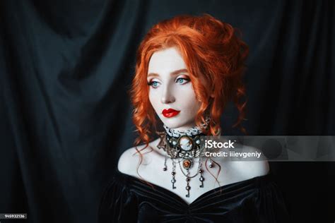 여자는 그녀의 목에 창백한 피부와 빨간 머리는 검은 드레스와 목걸이에 뱀파이어는 뱀파이어 발톱과 빨간 입술의 소녀 마녀 고딕 보세요입니다 할로윈의 상에 고딕 양식에 대한