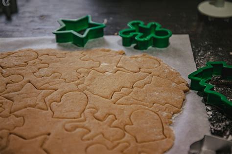 어두운 배경에 양피지 베이킹 종이에 원시 반죽에서 크리스마스 트리 스타 작은 남자 마음의 형태로 진저 브레드 쿠키를 잘라 맨 위