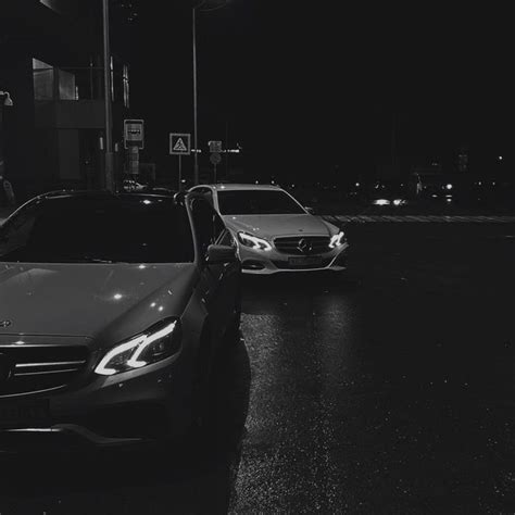 two cars are parked on the side of the road at night, one is black and ...
