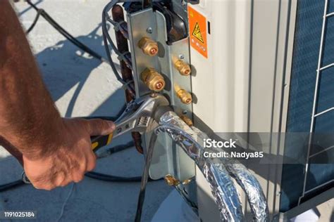 공조 기술자는 새로운 산업 건물 옥상에 에어컨 유닛을 가동하고 있습니다 에어컨의 실외 유닛을 조이기 위해 고정 렌치를 사용한 기술자 손 남자는 손에 렌치를 들고 있었다