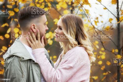 사랑에 부부는 가을 숲을 통해 산책 포옹과 남자와 여자의 키스 관계와 사랑 젊은 부부는 노란색 빨간 잔디에 서 소녀 손에 꽃다발 2명에 대한 스톡 사진 및 기타 이미지