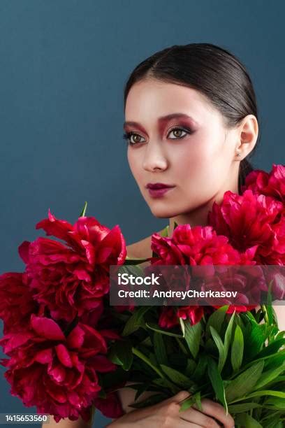 푸른 배경에 손에 꽃 모란을 가진 아름다운 소녀 봄 꽃다발과 함께 스튜디오에서 포즈를 취하는 즐거운 여성 모델 귀여운에 대한 스톡 사진 및 기타 이미지 Istock