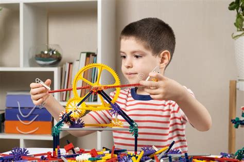 A Little Boy Plays With A Constructor Creating Figures From Gears And