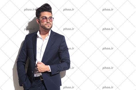 عکس با کیفیت مرد خوشتیپ و خوش چهره با کت و شلوار سرمه ای و پیراهن سفید و با ژست گرفتن یقه ی کت