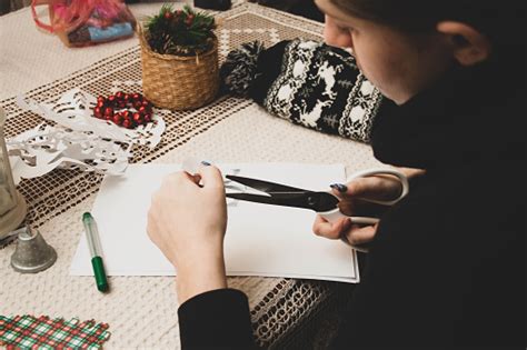 소녀는 크리스마스 나 새해를 축하하기 위해 종이에서 눈송이를 잘라 흰색과 색종이 가위 마커 화이트 레이스 식탁보에 계절 장식 Diy에 대한 스톡 사진 및 기타 이미지