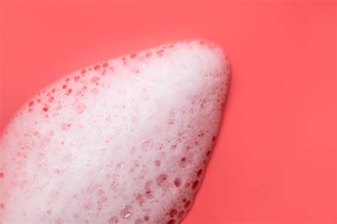분홍색 배경에 거품이 있는 하얀 거품의 질감 세척 위생 샴푸 비누 목욕 젤 무스를위한 화장품 거품 최소한의 미용 및 의료 배경