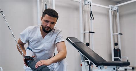 전문 물리 치료사는 재활 센터 치료실에 부착 된 재활 장비 밧줄로 여성의 무릎을 구부립니다 물리 치료사는 저항 테이프로 여성 다리를 당깁니다 사진 Unsplash의