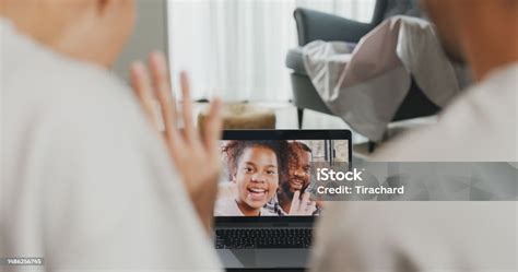 행복한 젊은 아시아 커플은 소파에 앉아 노트북 화면을 보며 웃으며 휴일에 집에 있는 친구들과 화상 통화를 한다 젊은 남편과 아내 웹캠 대화 인터넷 연결을 미소 짓는다 가정