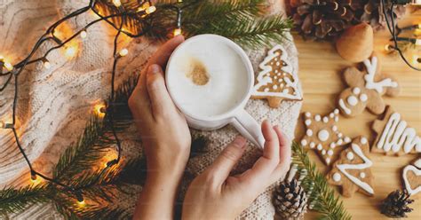 크리스마스 진저 브레드 쿠키 아늑한 니트 스웨터 소나무 콘과 조명이있는 전나무 가지를 배경으로 따뜻한 커피를 들고 있습니다 안녕하세요 겨울 분위기 있는 이미지