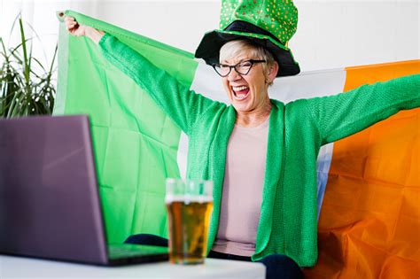 컴퓨터에서 게임을보고 맥주를 마시고 아일랜드 국기와 레프레바운 모자로 아일랜드를 응원하는 아일랜드 여성 Championship에 대한 스톡 사진 및 기타 이미지 Istock