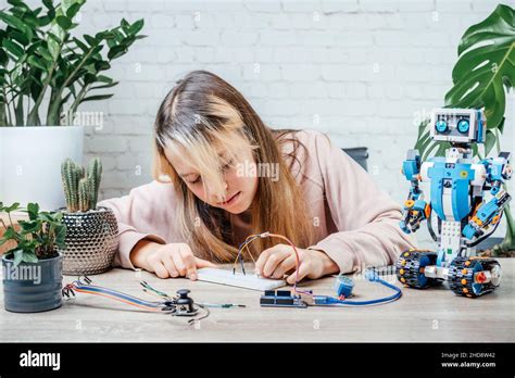 a teenager girl plugging cables to sensor chips while learning arduino coding and robotics stock