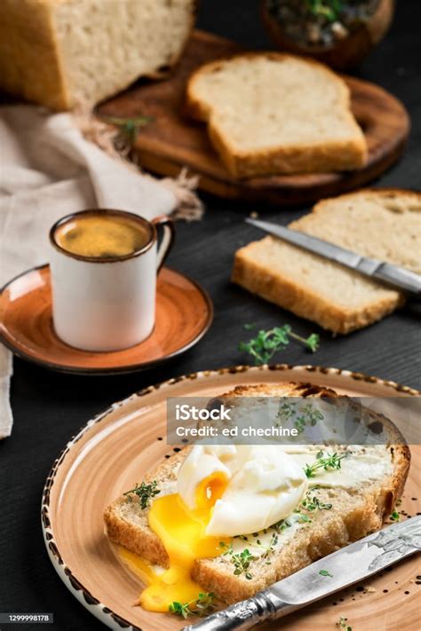 버터 크림과 허브로 덮인 빵 조각에 부드러운 삶은 달걀 검은 나무 테이블에 점토 접시에 흐린 배경에 에스프레소 커피와 얇게 썬