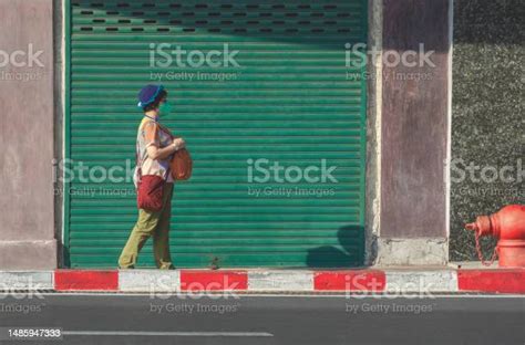 보호 마스크를 쓴 아시아 여성 관광객은 건물 벽 배경에 햇빛과 그림자가 있는 보행자 통로를 걷고 있다 도시에 대한 스톡 사진 및 기타 이미지 Istock