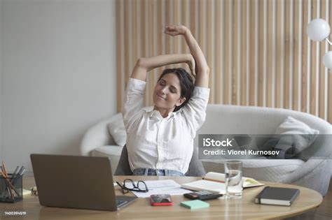 피곤한 이탈리아 숙녀 원격 직원이 노트북으로 책상에 앉아있는 동안 팔을 스트레칭 연장전에 대한 스톡 사진 및 기타 이미지 연장전 자유 책상 Istock