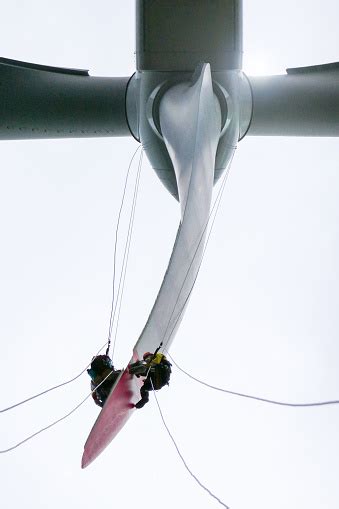 두 명의 전문 로프 액세스 기술자 산업 등반가 가용 및 밧줄에 풍력 터빈의 블레이드 의 끝에서 협력 검사 및 수리 세레이션과 Fibber 유리 그들은 바로 위에 있습니다