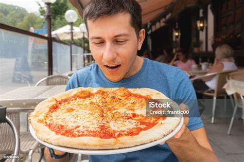 피자 가게에서 갓 구운 맛있는 마가리타와 뜨거운 피자를 먹는 행복한 청년 정통 이탈리아 요리를 제공하는 카페와 레스토랑 남자에 대한 스톡 사진 및 기타 이미지 Istock