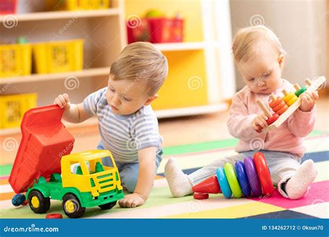 Дети играют с воспитательными игрушками Дети сидят на половике в