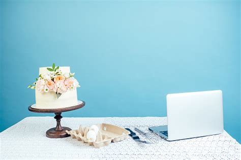 Copyspace 모형 작업 공간 베이커 과자 패스트리 요리사 크리미한 화이트 이층 결혼식 케이크와 테이블에 신선한 꽃 노트북과